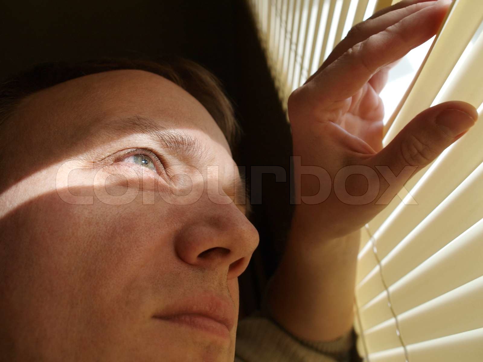 Man looking through blinds | Stock image | Colourbox