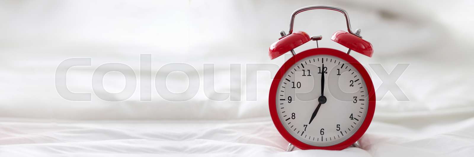 Red alarm clock on a white blanket, close-up - Stock Image - Everypixel