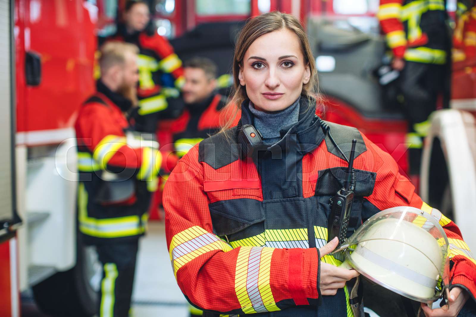Beautiful fire fighter woman with her helmet standing in the firehouse ...