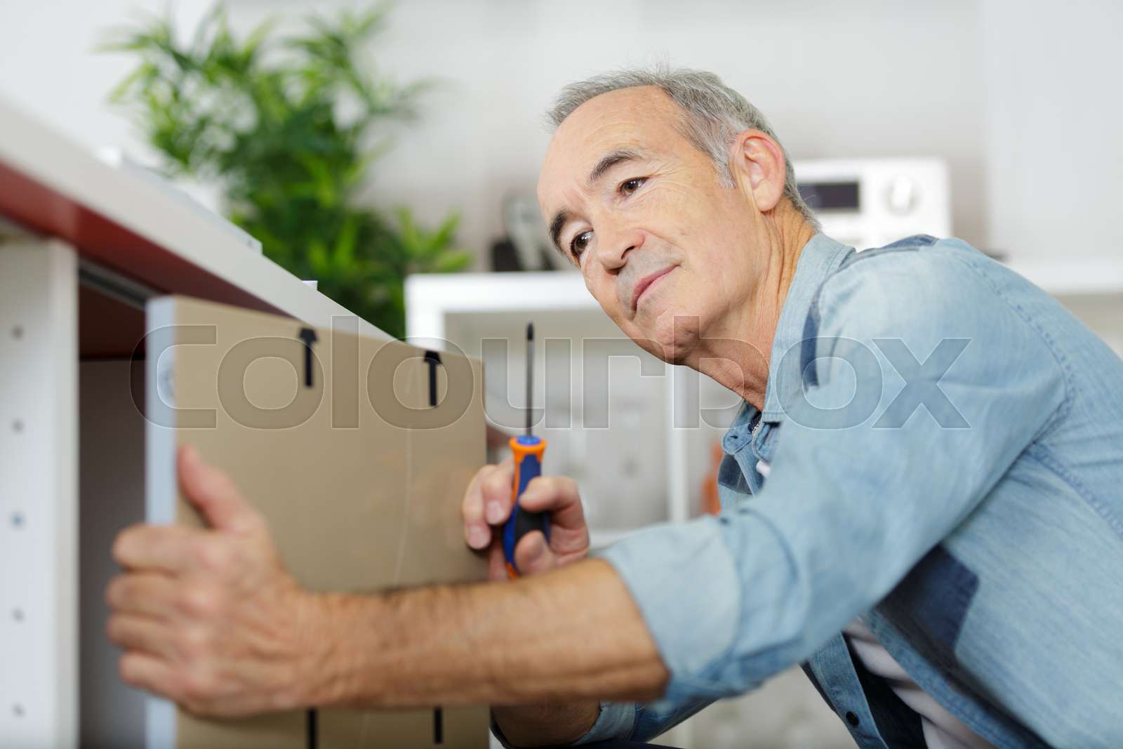 senior man assembling kitchen cupboard | Stock image | Colourbox