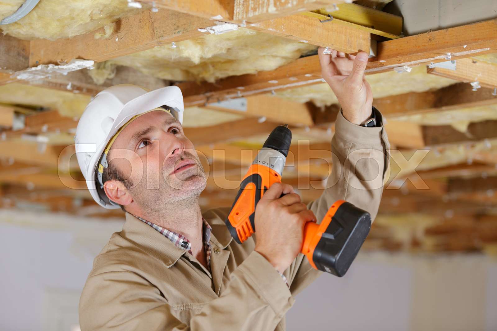 man drilling a hole in white ceiling | Stock image | Colourbox