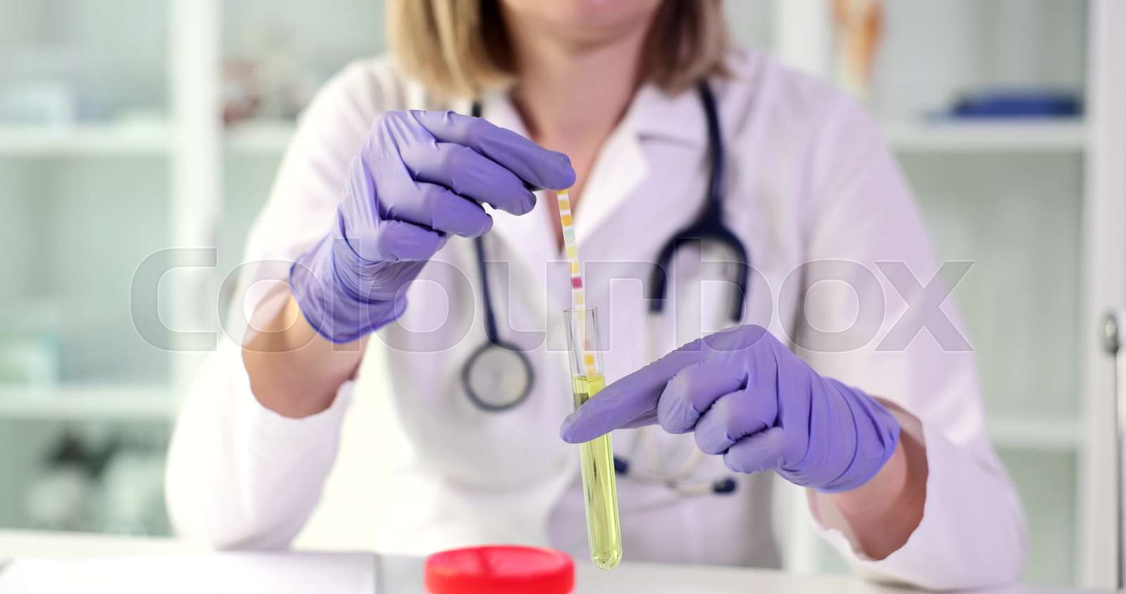 Doctor urologist lowering test strip into tube for express urine ...