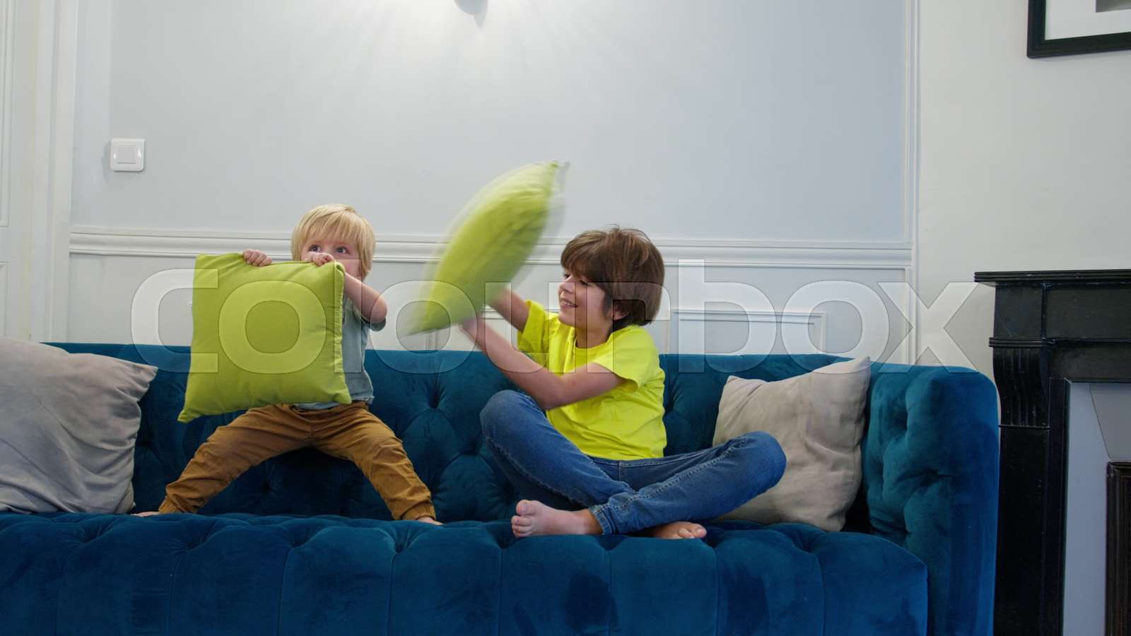 Two children fight with pillows sitting on the couch | Stock video ...