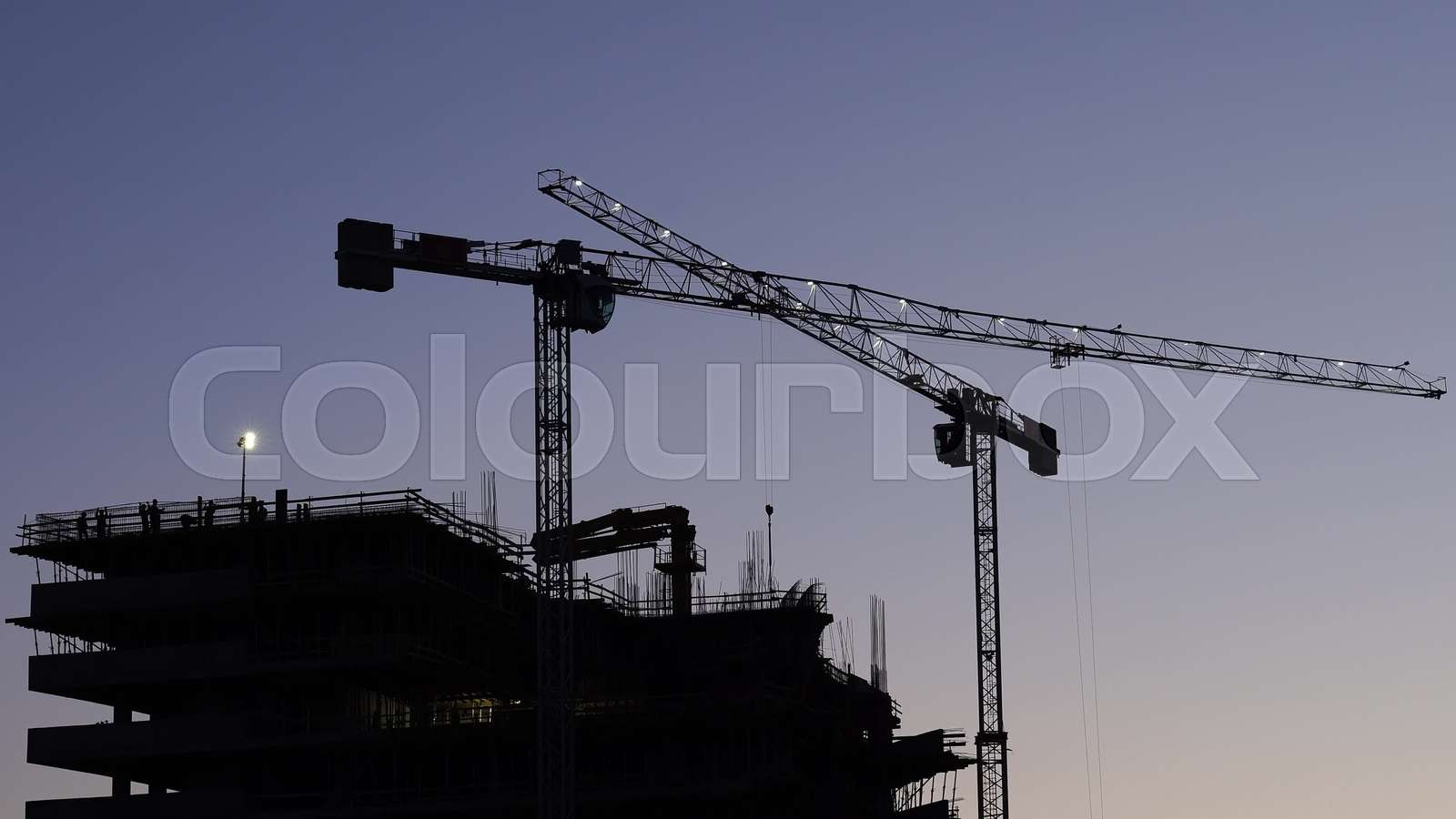 Illuminated Tower Crane Works At The Construction Site Of A Multi