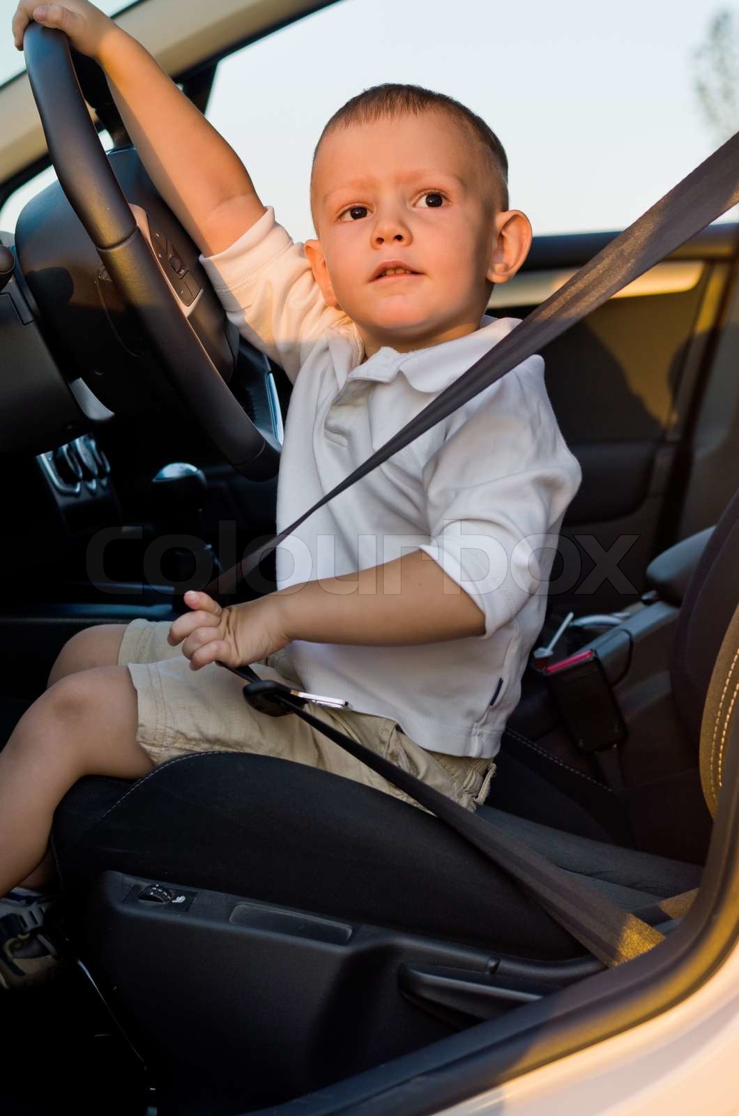 Cute little boy in the drivers seat of a car | Stock image | Colourbox