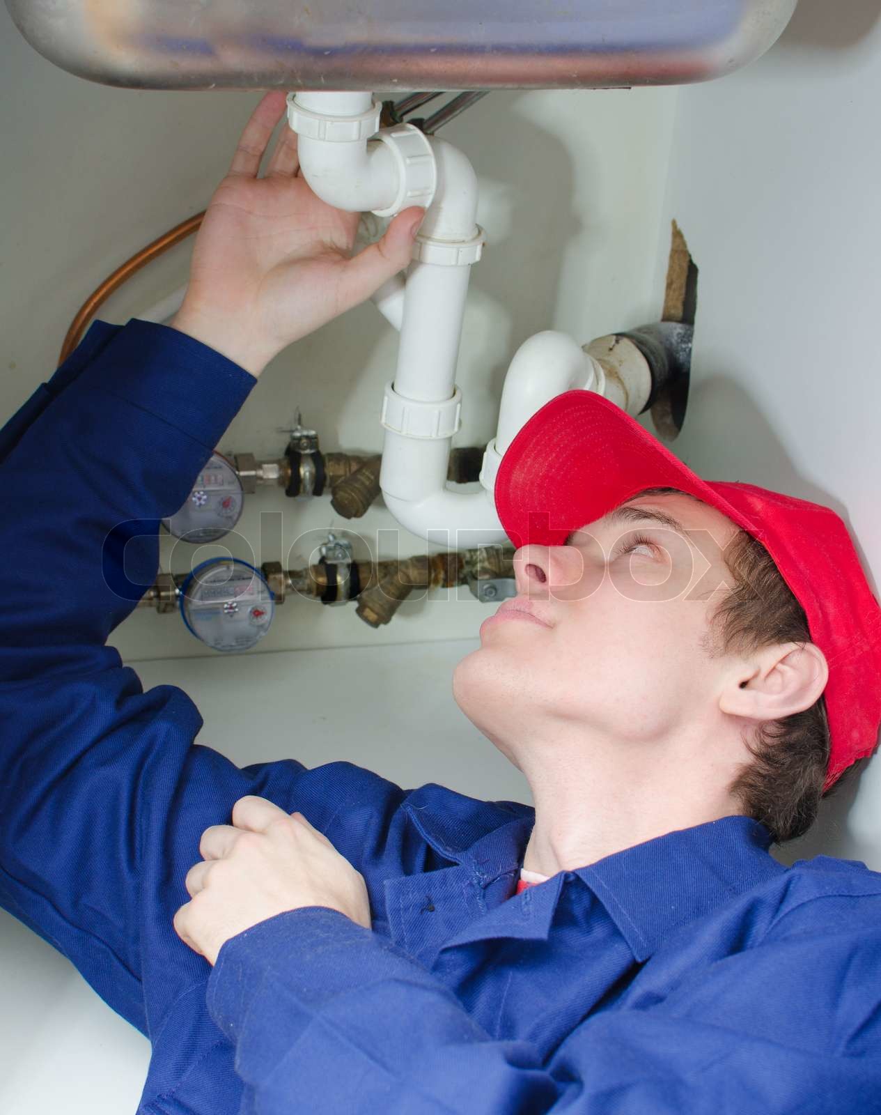 Plumber in uniform repairing pipeline in the house | Stock image ...