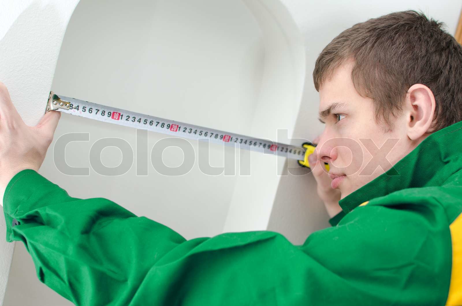 Junge Handwerker in Uniform arbeiten mit Maßband | Stock Bild | Colourbox