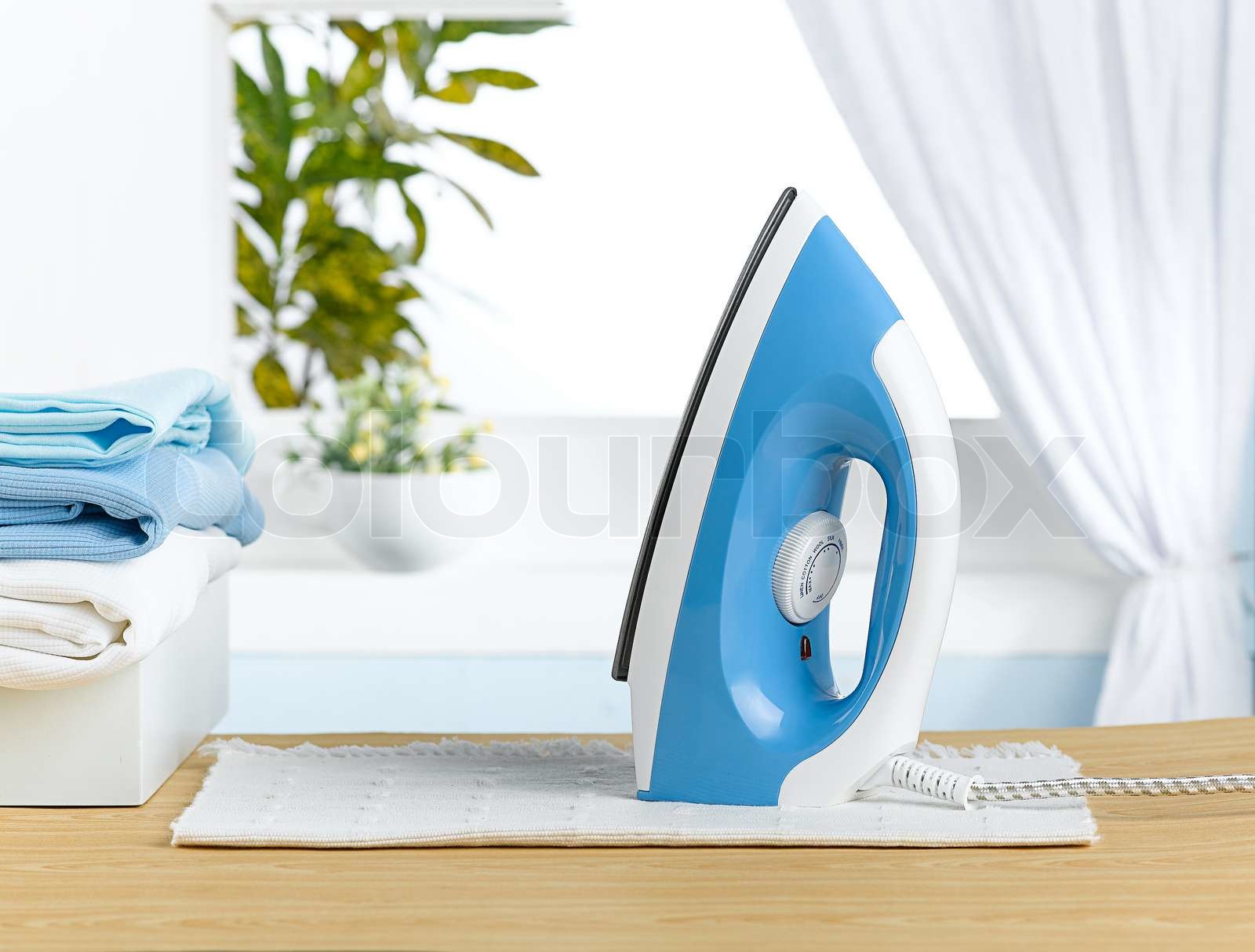 Steam iron in the laundry room interior | Stock image | Colourbox
