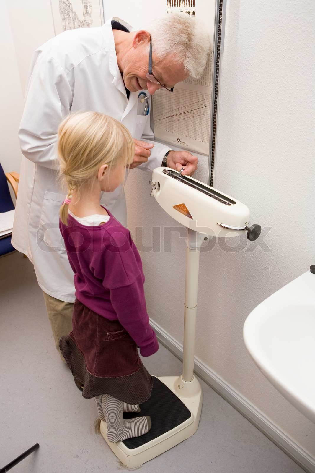 A doctor weighing a child on a scale | Stock image | Colourbox