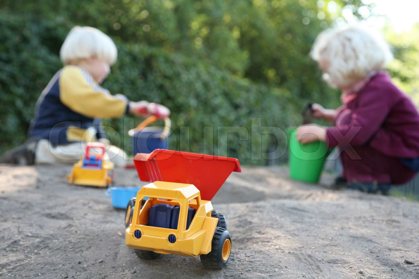 Blurred image of two blond kids playing on sandy playground | Stock ...