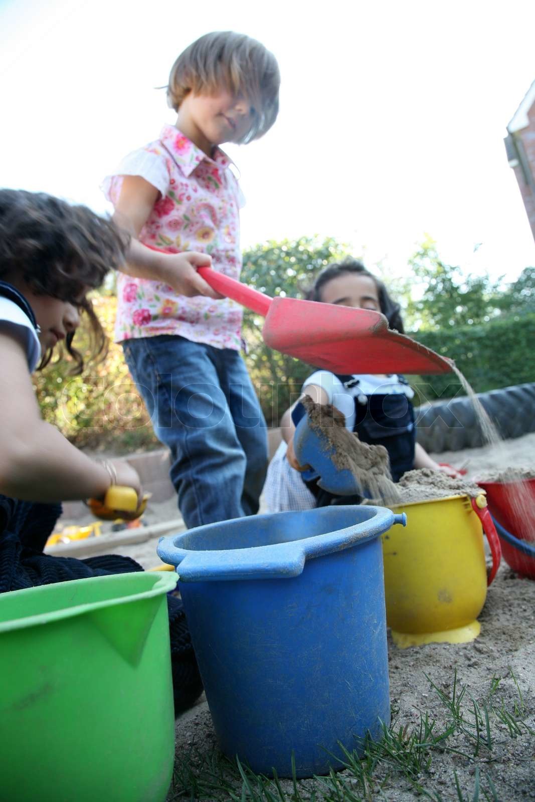 Kids pouring sand into buckets on palyground | Stock image | Colourbox
