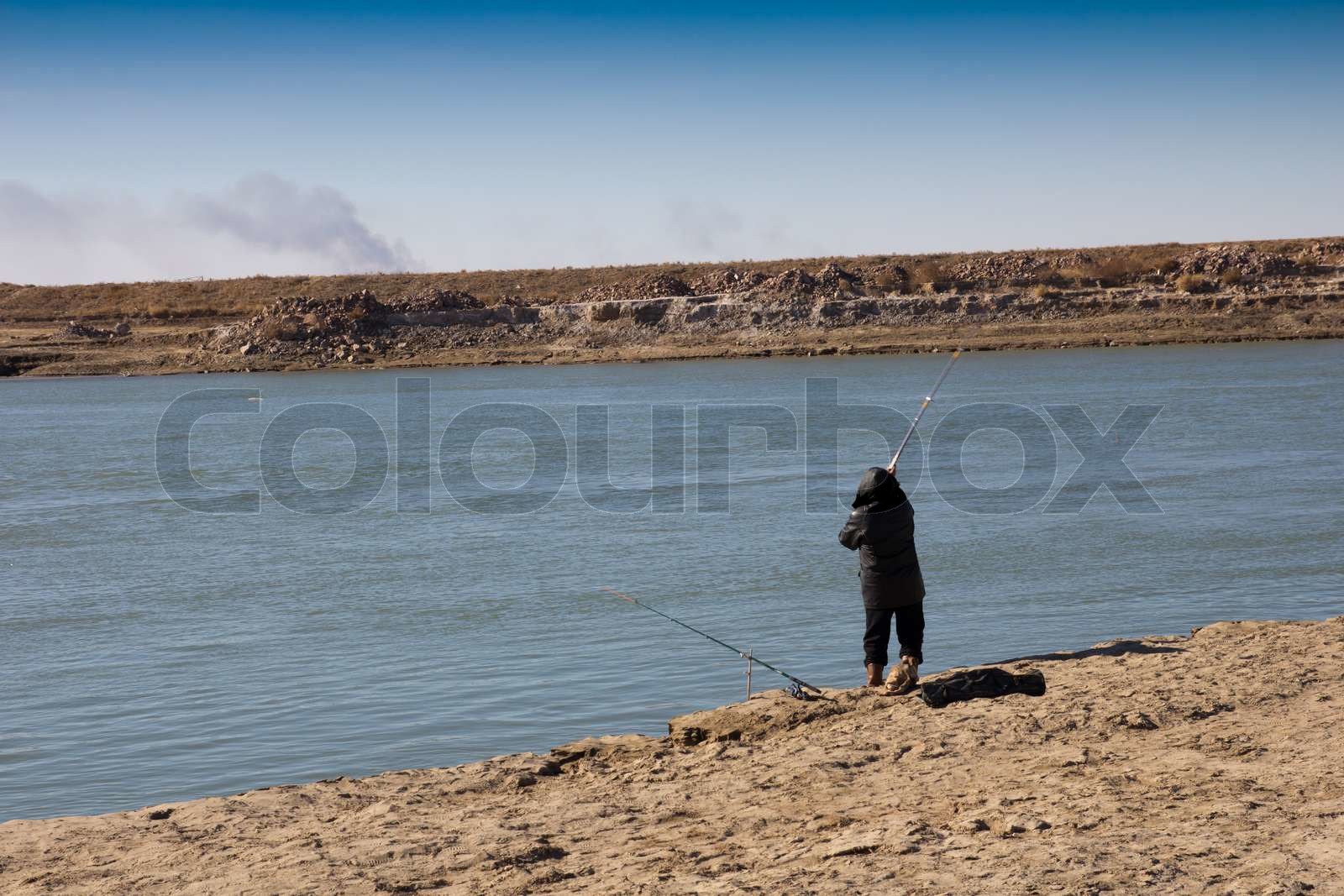 fisherman catching a fish on a fishing tackle in the river | Stock ...