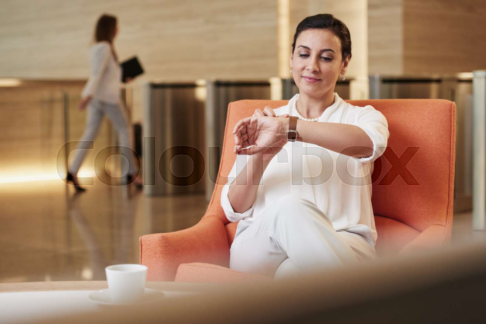 Business woman checking her watch while sitting in airport waiting ...