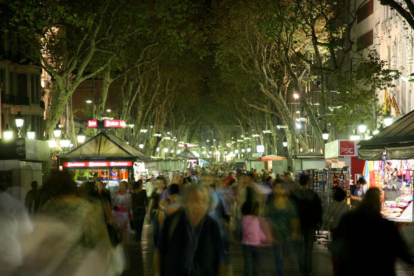 Crowded pedestrian path with blurred people in Barcelona at night ...