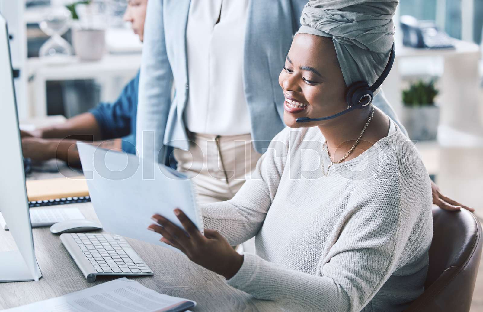 African american call centre telemarketing agent reading paperwork ...