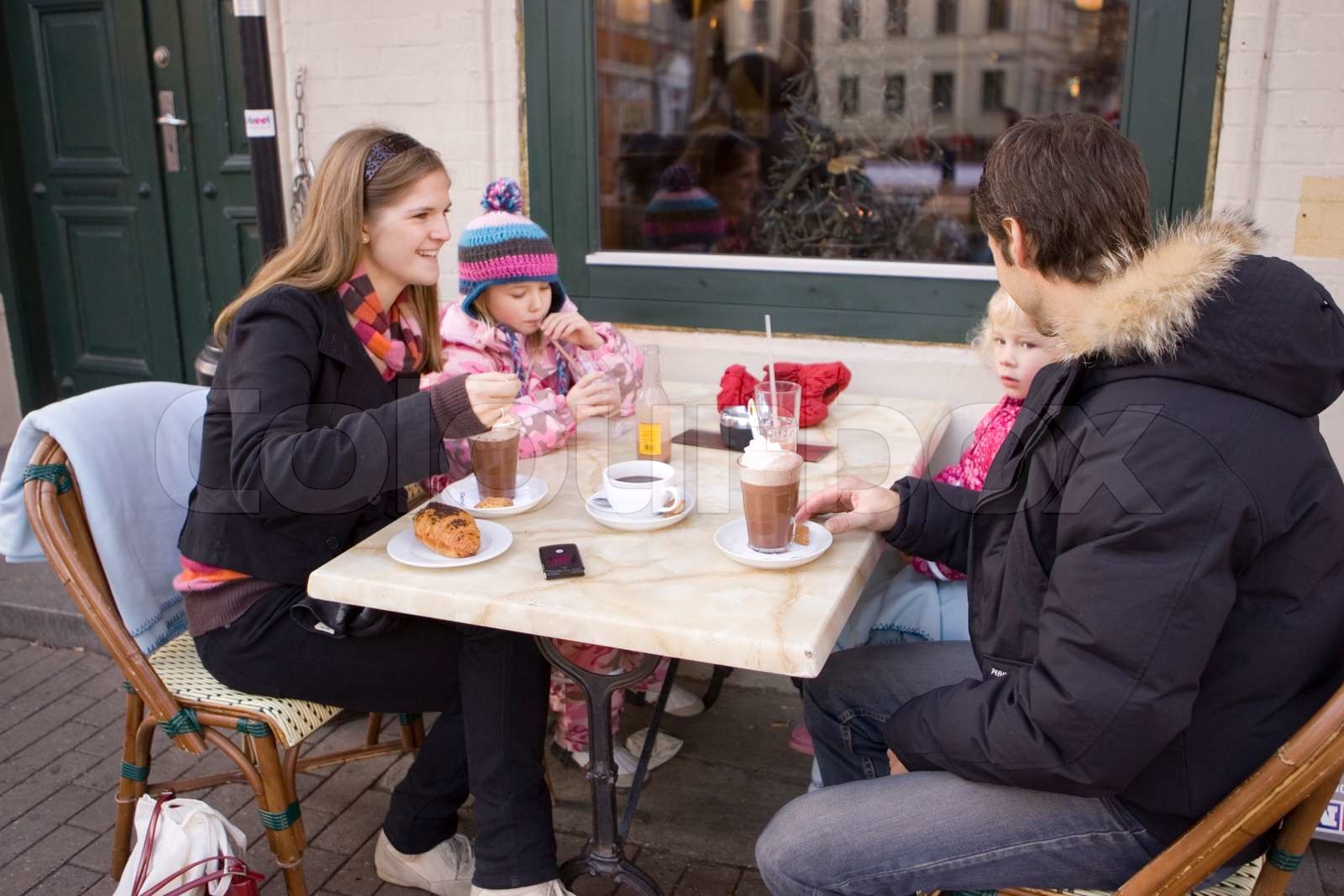 A couple and their children having snack in a coffee place | Stock ...
