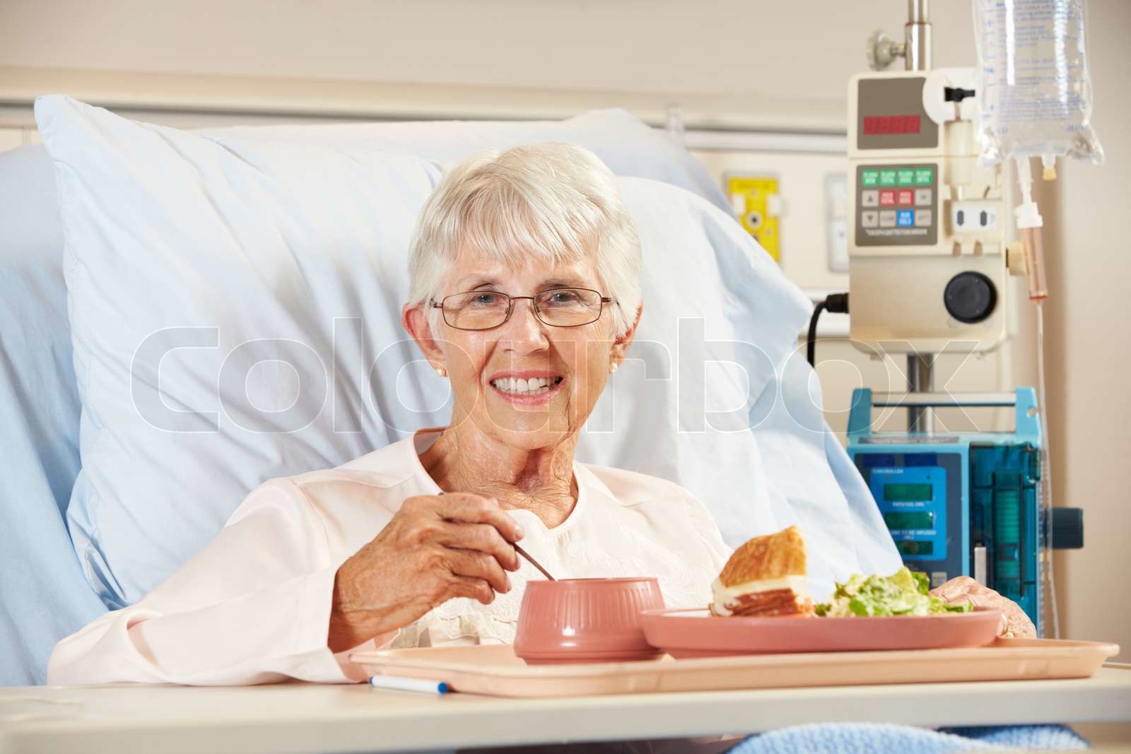 Senior Female Patient Eating Meal In Hospital Bed | Stock image | Colourbox