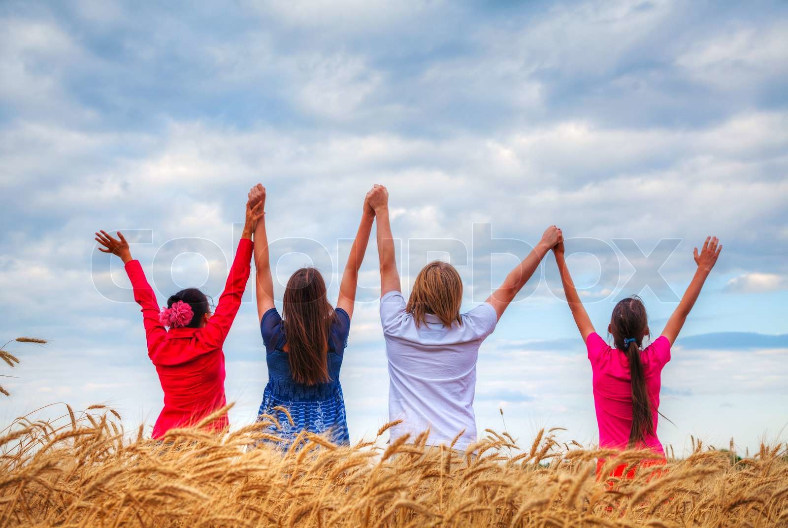 Four young people staying with raised hands | Stock image | Colourbox