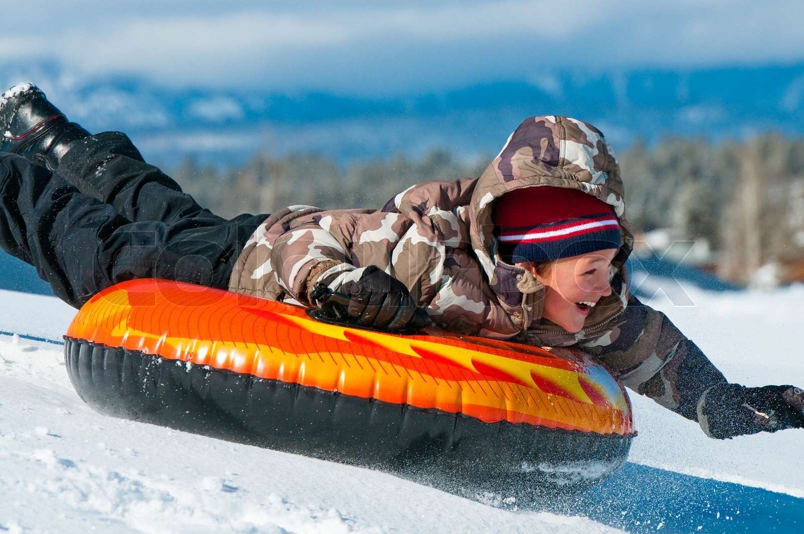 Happy boy riding a tube in snow | Stock image | Colourbox