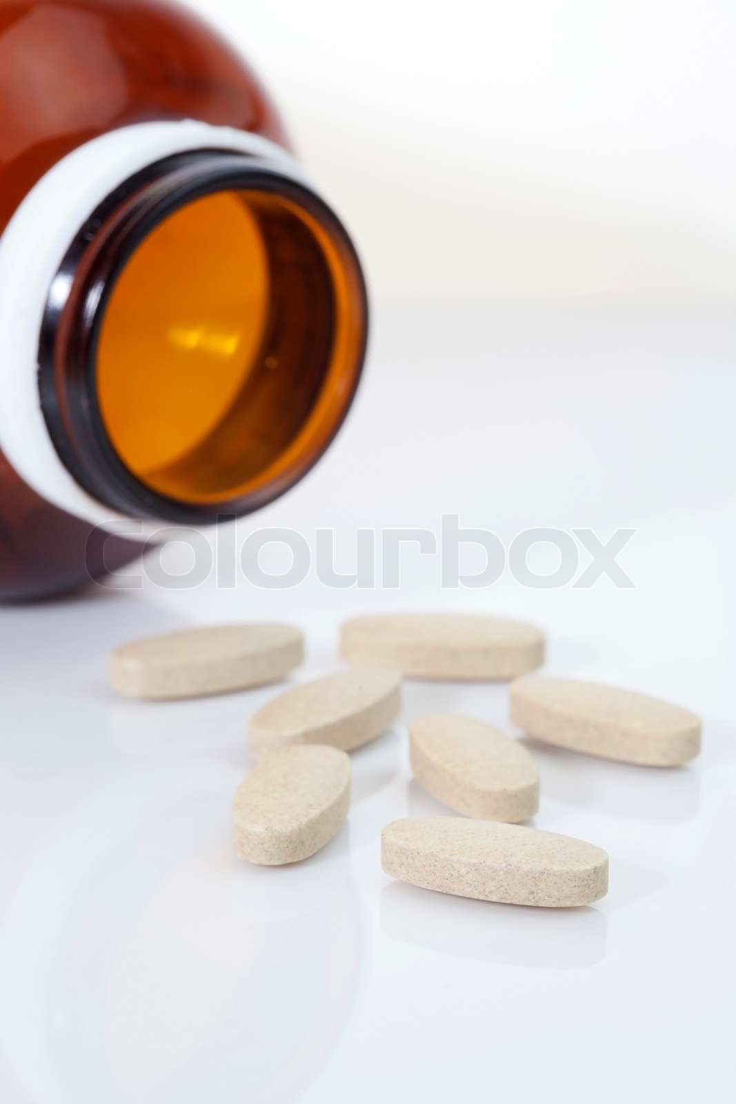 Open pill bottle with medicine spilling out | Stock image | Colourbox