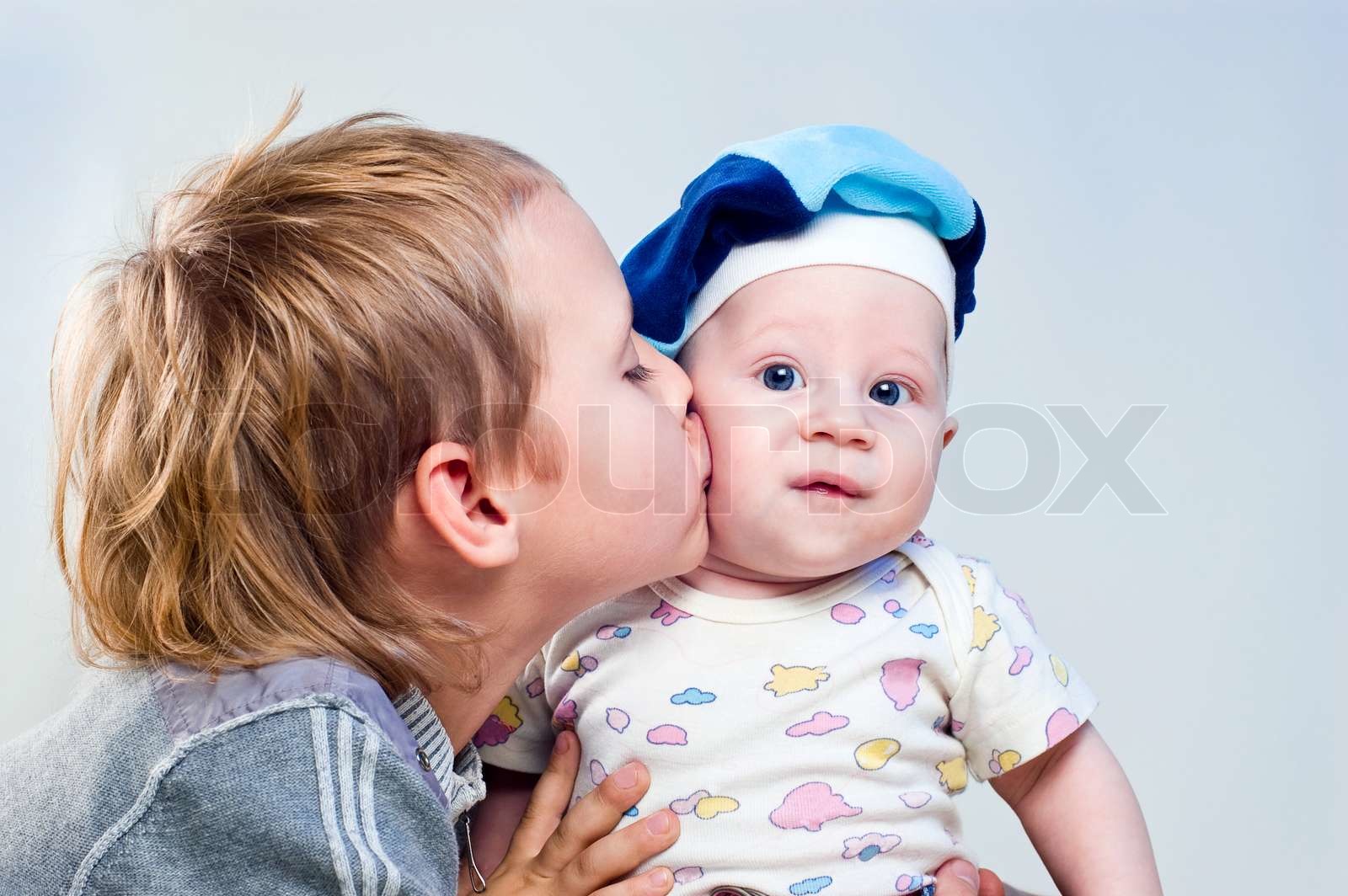 Elder brother kisses in a cheek junior brother | Stock image | Colourbox