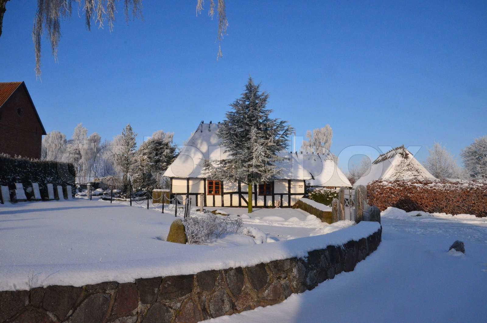 vinter i landby med sne på gammelt hus med stråtag og bindingsværk og ...