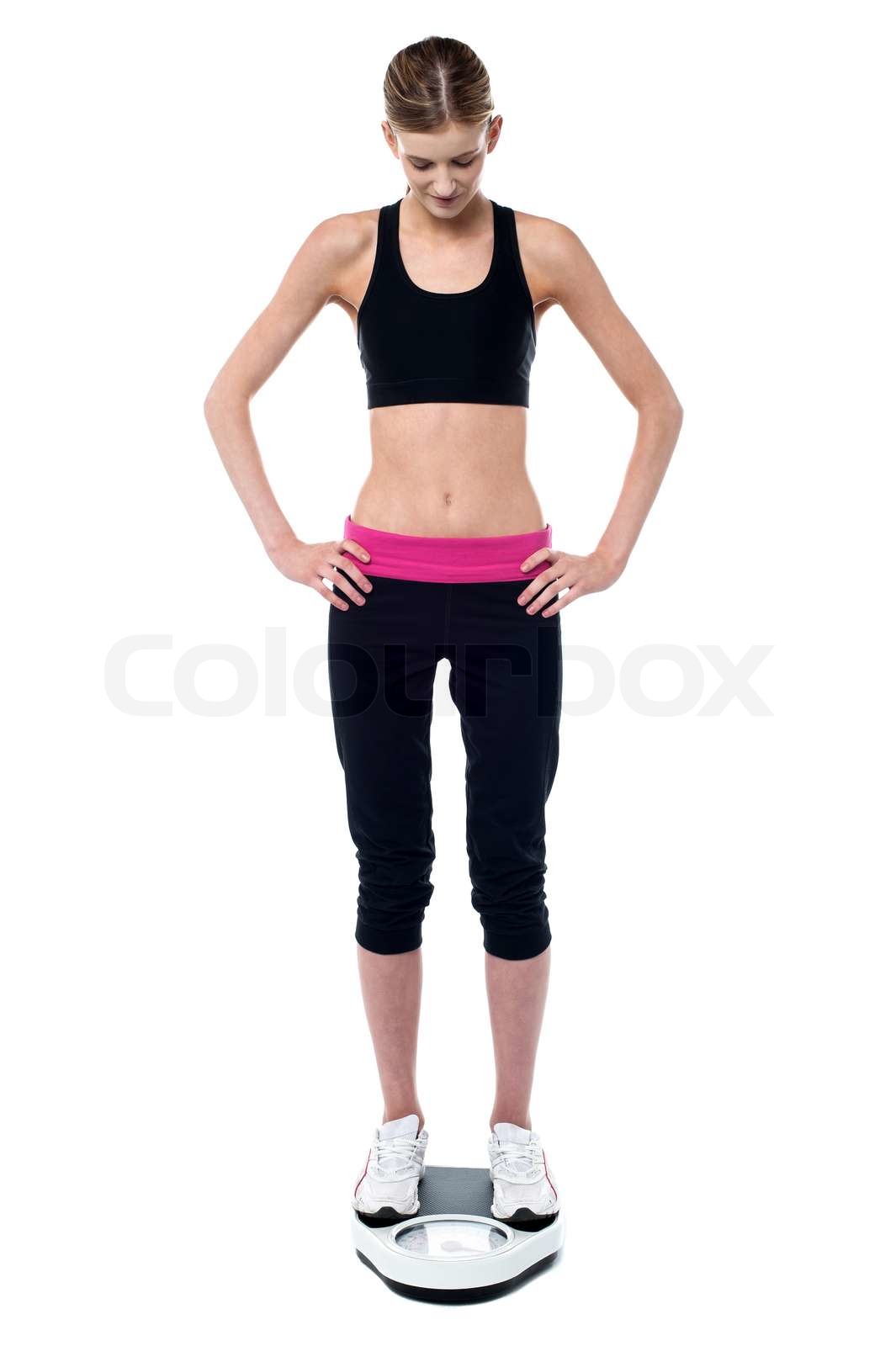 Slim fit tall girl measuring her weight | Stock image | Colourbox
