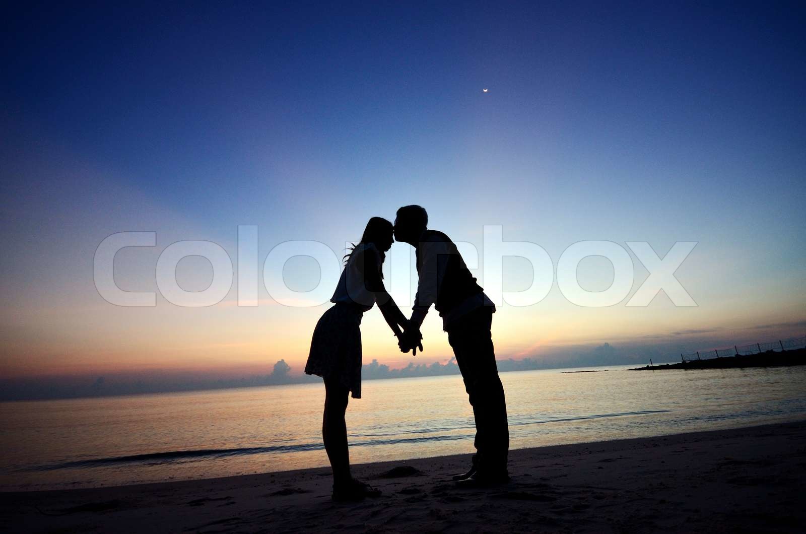 Man kysser kvinde på panden, silhuet før solopgang | Stock foto | Colourbox