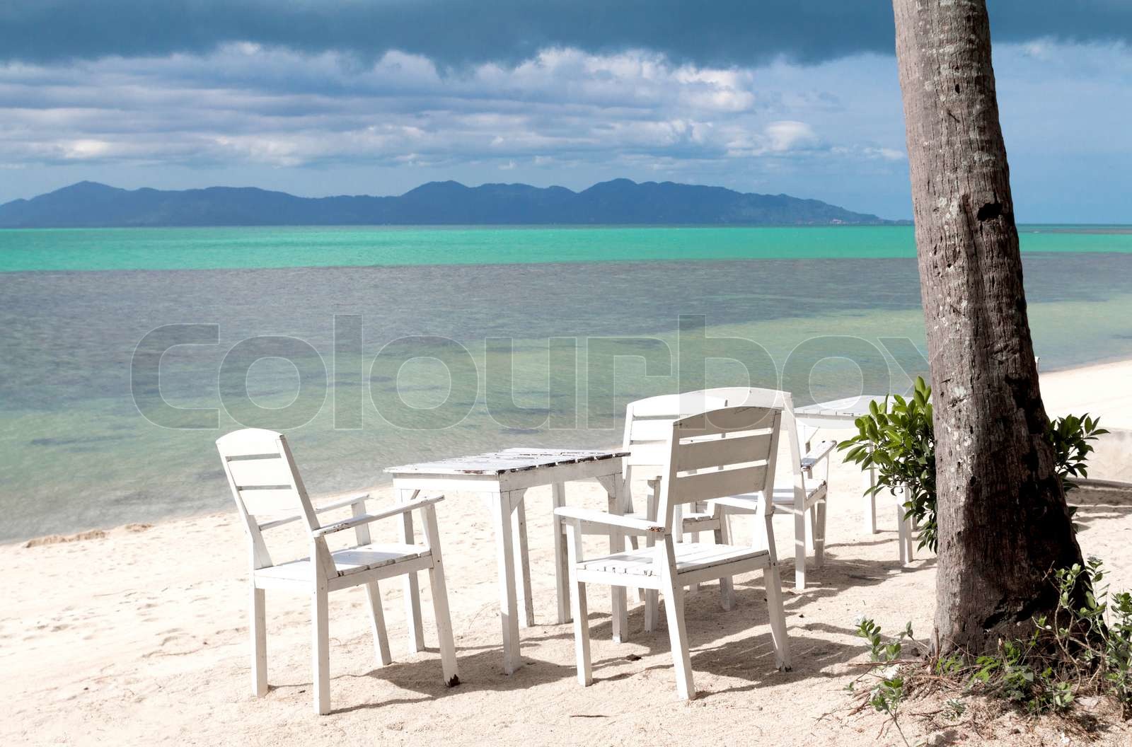 White table set on sand beach facing the ocean | Stock image | Colourbox