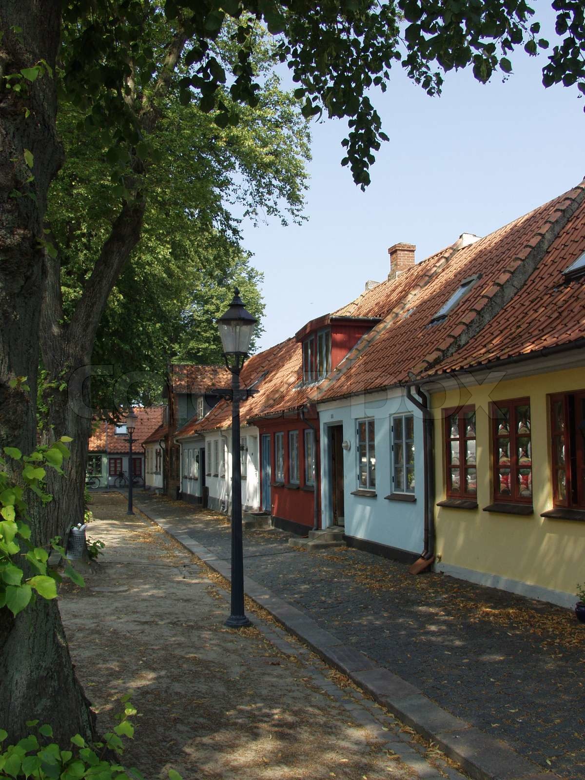 gamle små huse i forskellige farver og med røde tegltage, brosten og ...