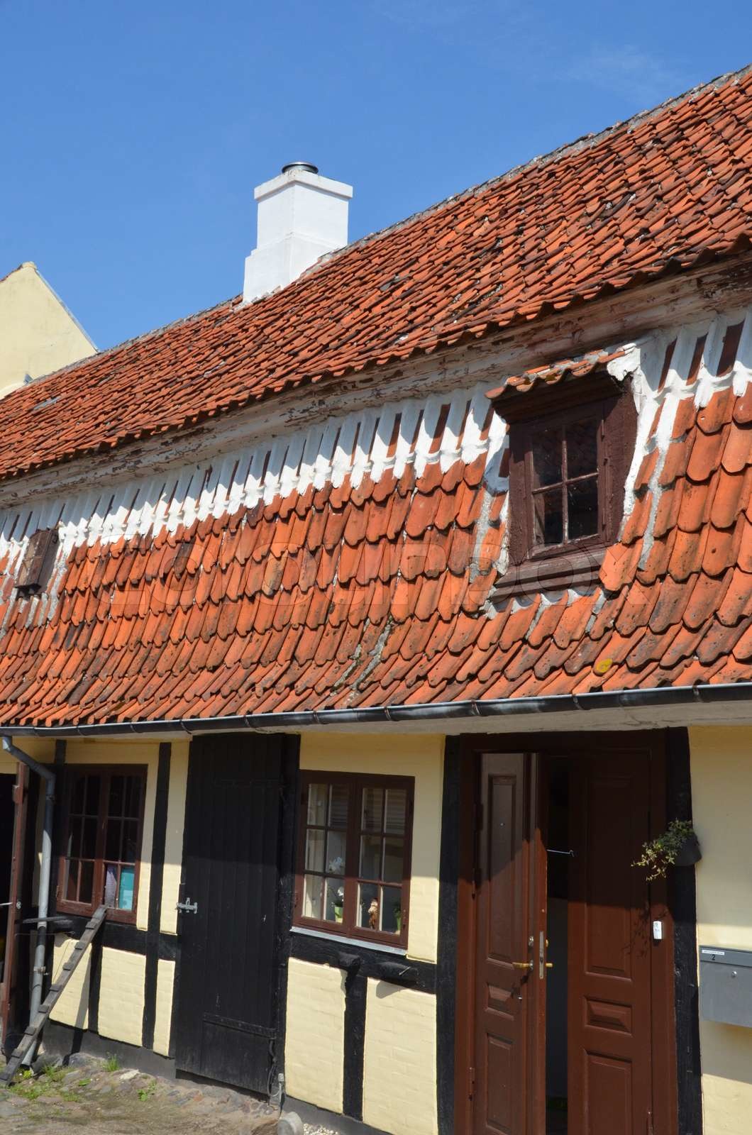 gammelt brunt kvist vindue i rødt tegltag med hvide fuger på gammelt ...