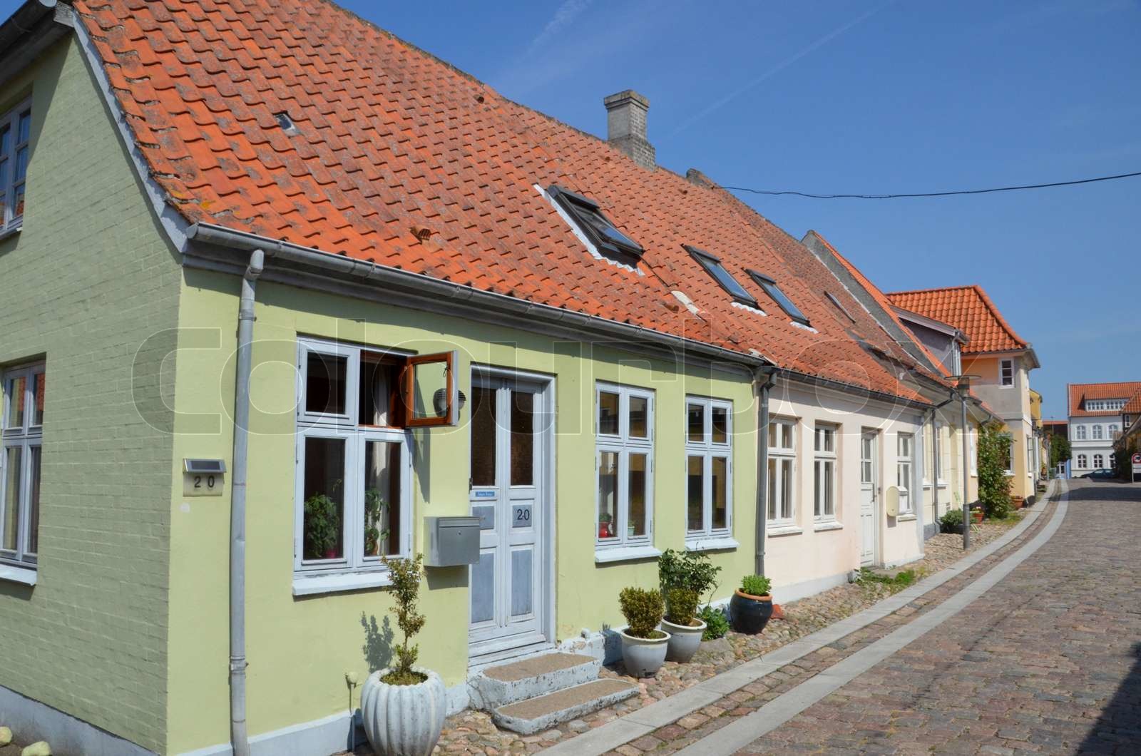 gade og vej med gamle sammenbyggede huse i forskellige farver med røde ...