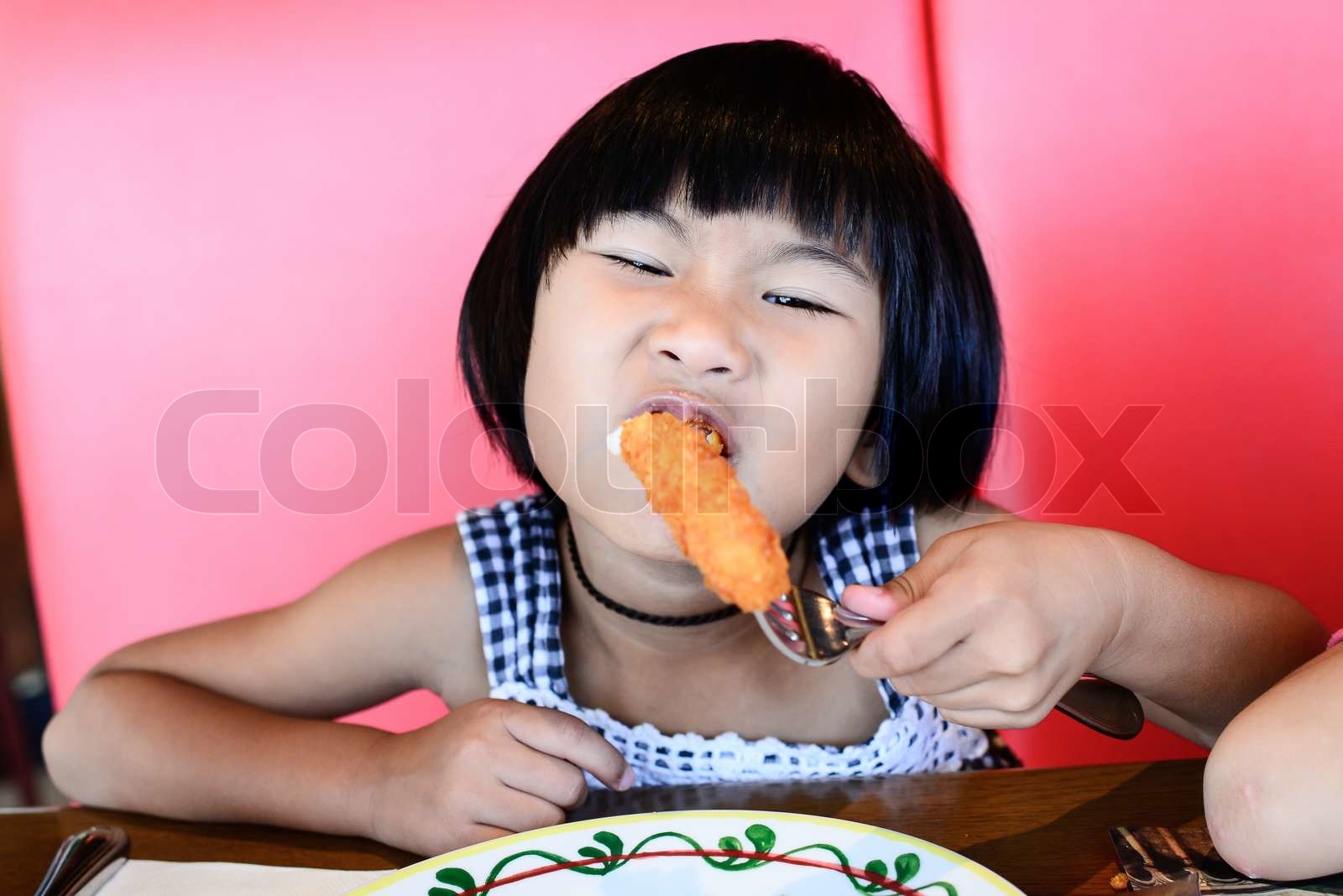 Girl eating fish finger | Stock image | Colourbox