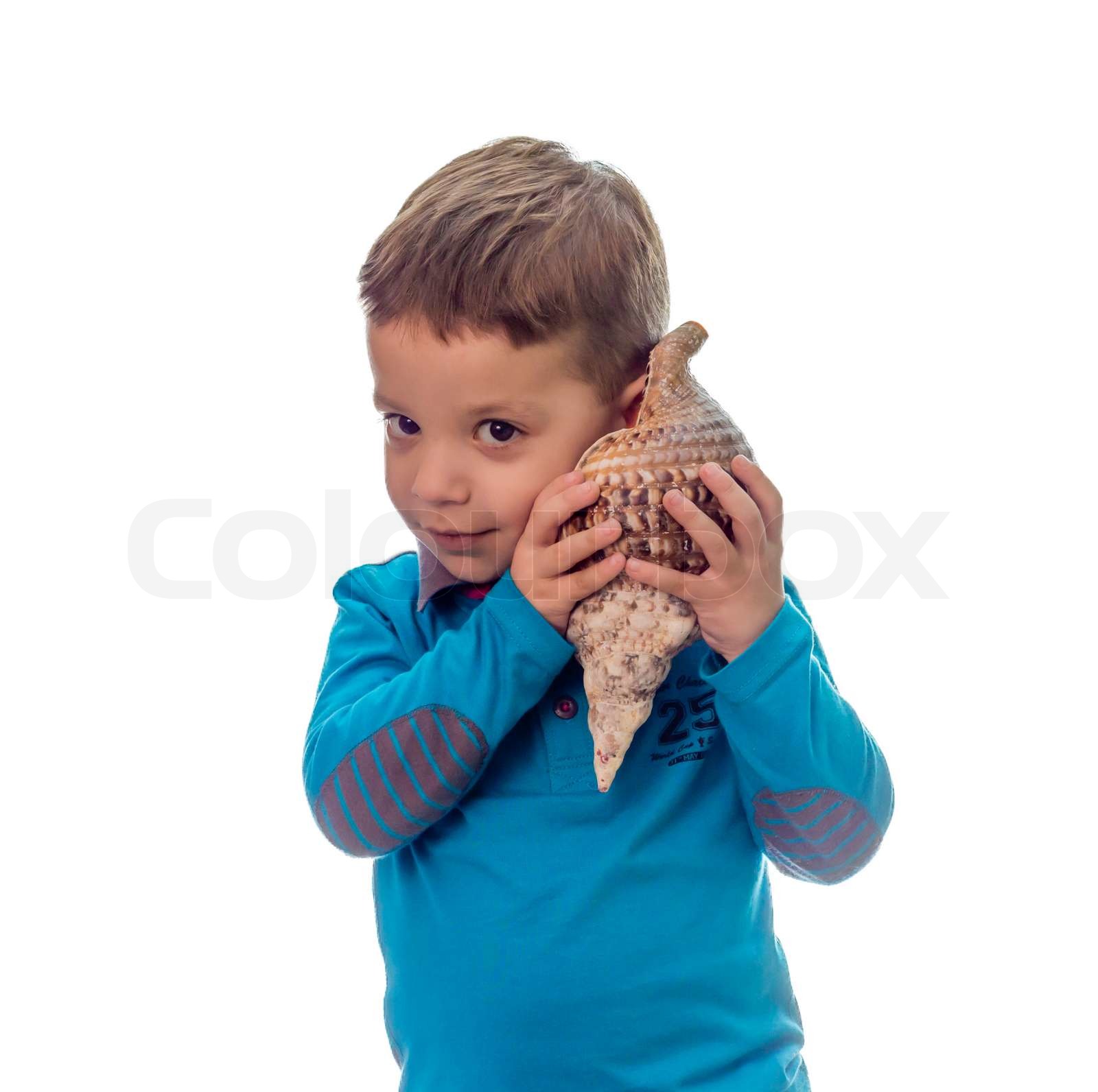 Boy hört das Meer durch eine Muschel | Stock Bild | Colourbox
