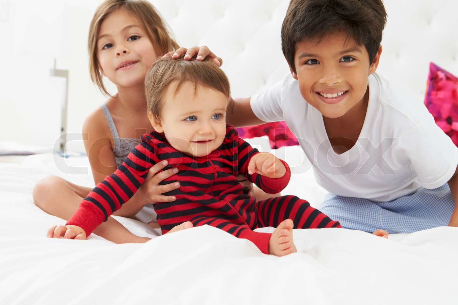Kinder sitzen auf dem Bett im Schlafanzug Zusammen | Stock Bild | Colourbox