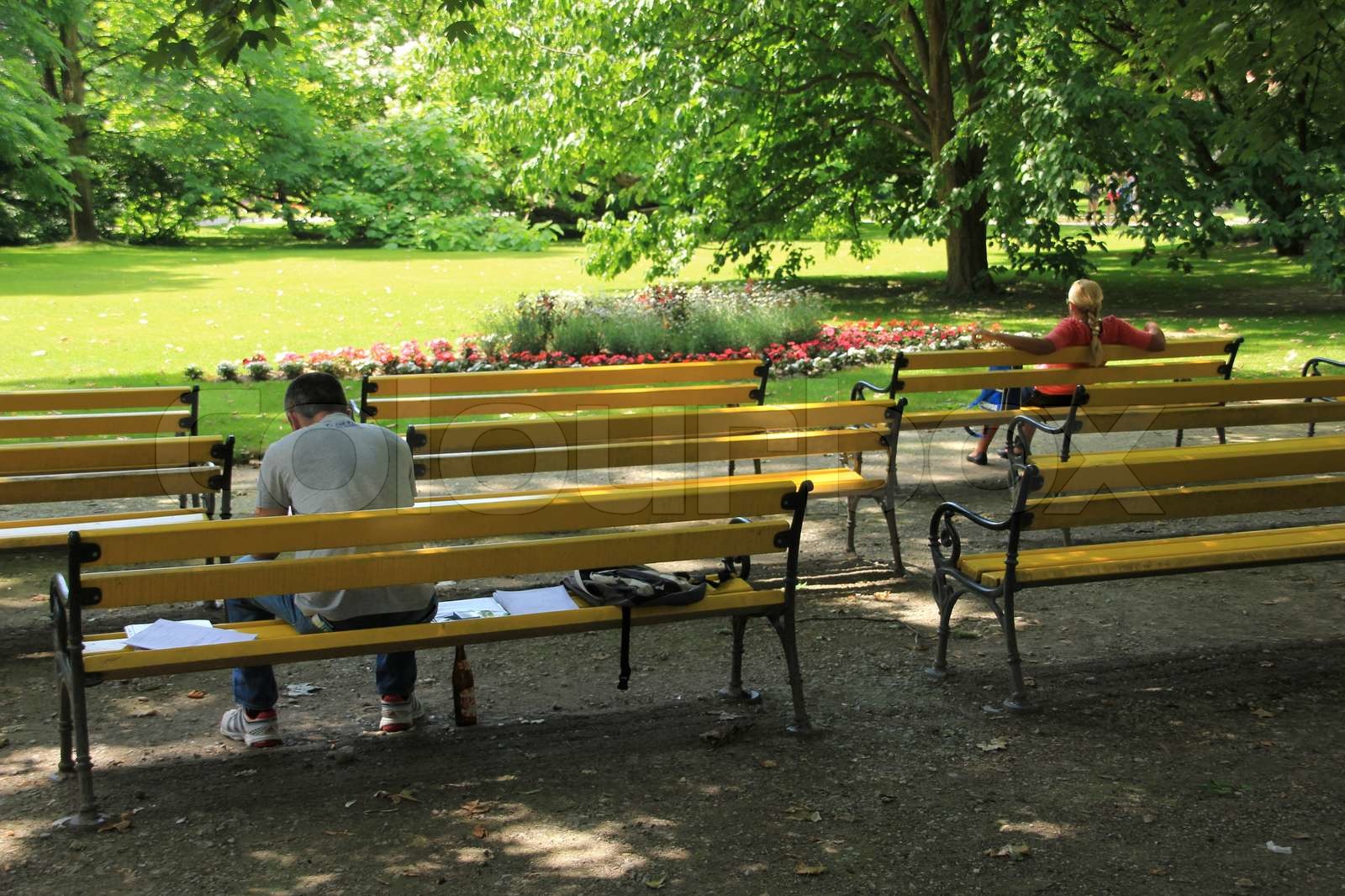 The man and lady sitting on bench have a break in municipal park in the ...