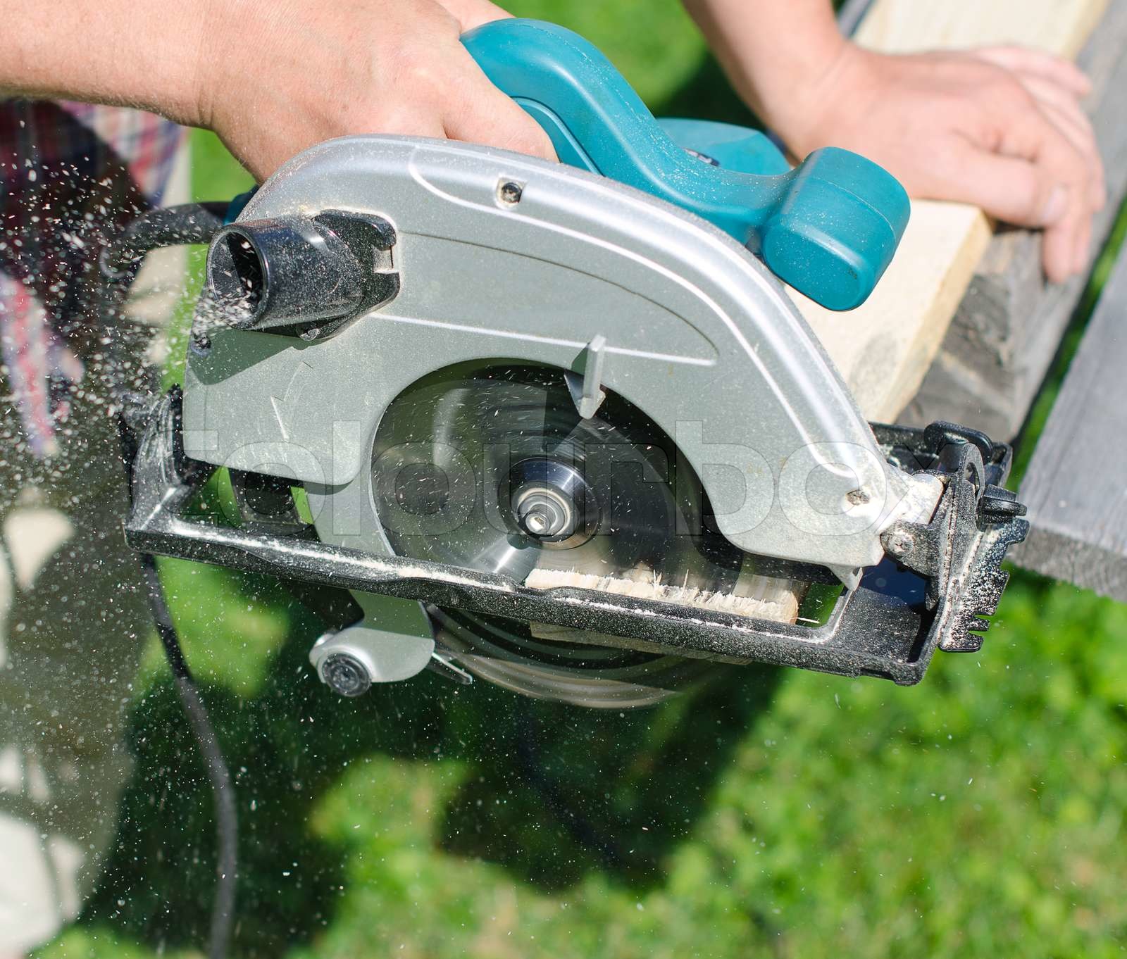 Handyman using hand-held saw machine outdoors | Stock image | Colourbox