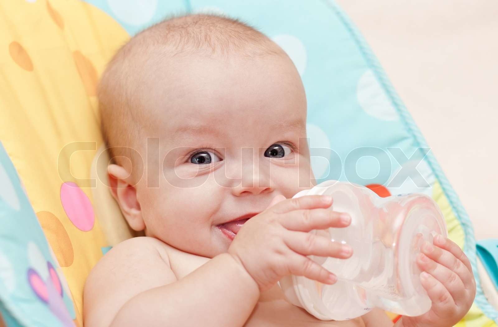 happy baby holding bottle and drinking water | Stock image | Colourbox