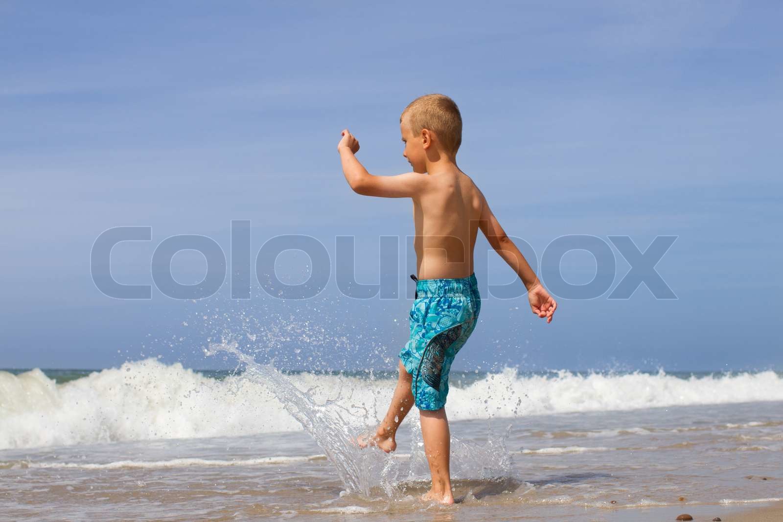 Boy splashing water at beach | Stock image | Colourbox