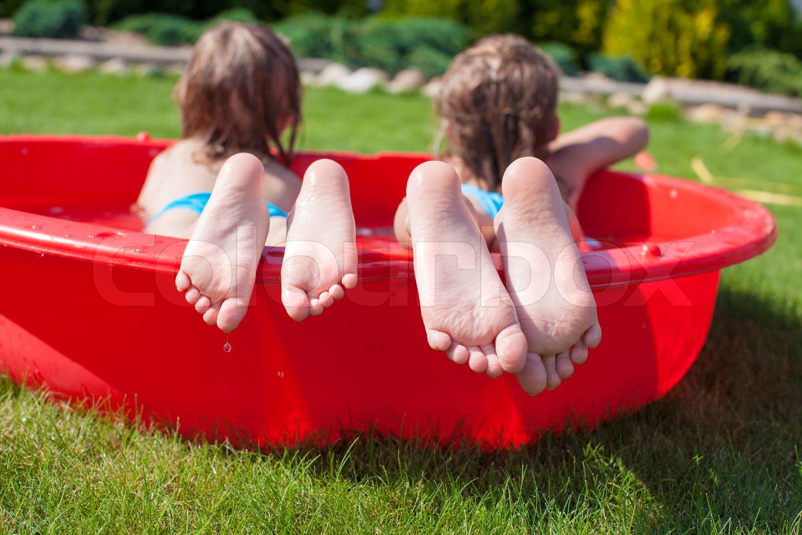 Close-up of feet two sisters in small pool | Stock image | Colourbox