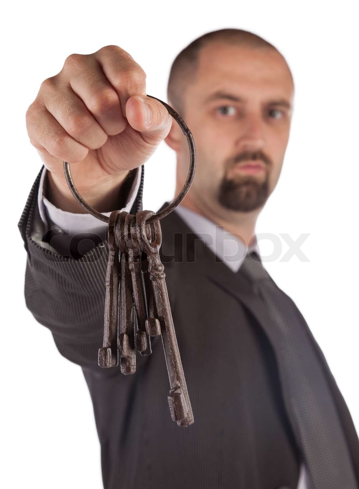 Man in suit giving old keys to a house | Stock image | Colourbox