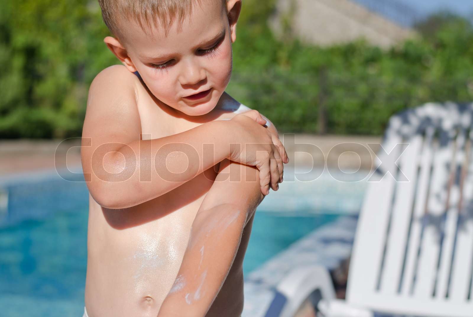 Young boy carefully applying sunscreen | Stock image | Colourbox