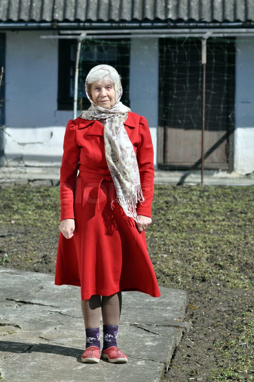 An old woman in red and shawl in front of her house | Stock image ...
