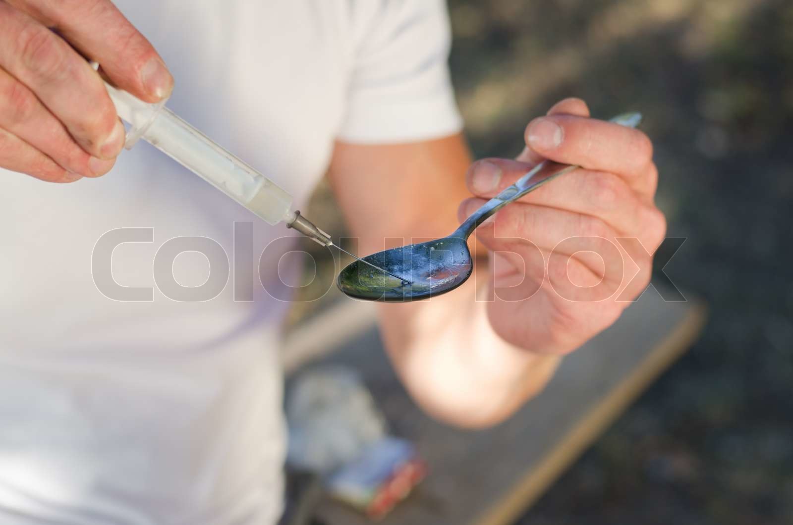 Drug user filling a syringe with crack cocaine | Stock image | Colourbox