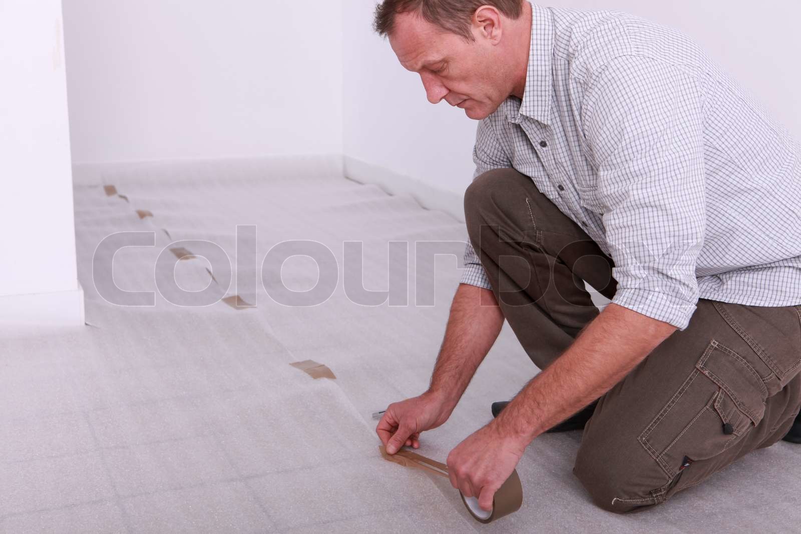 Man taping down underlay | Stock image | Colourbox