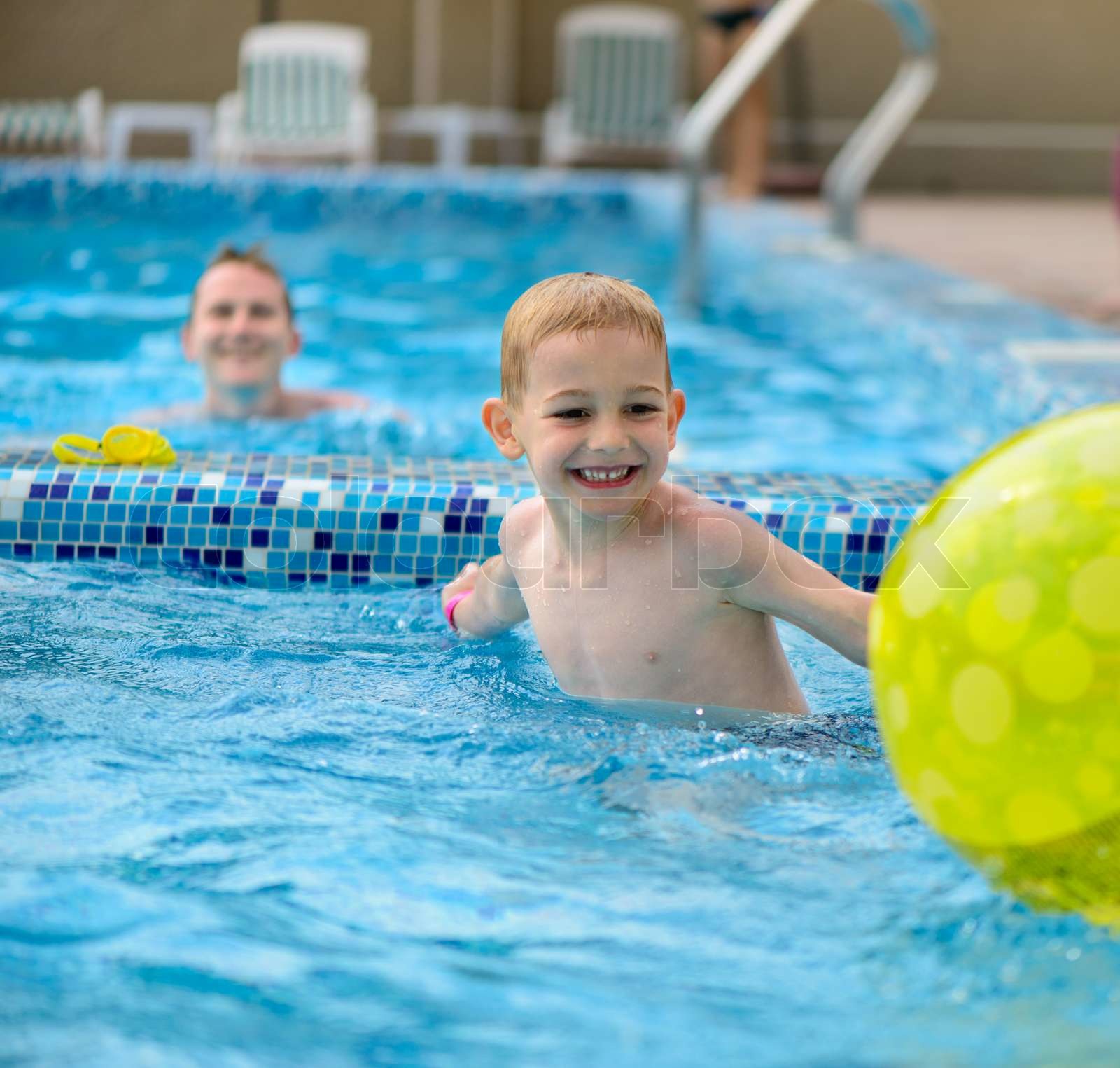 Happy father and son playing with ball in swimming pool | Stock image ...