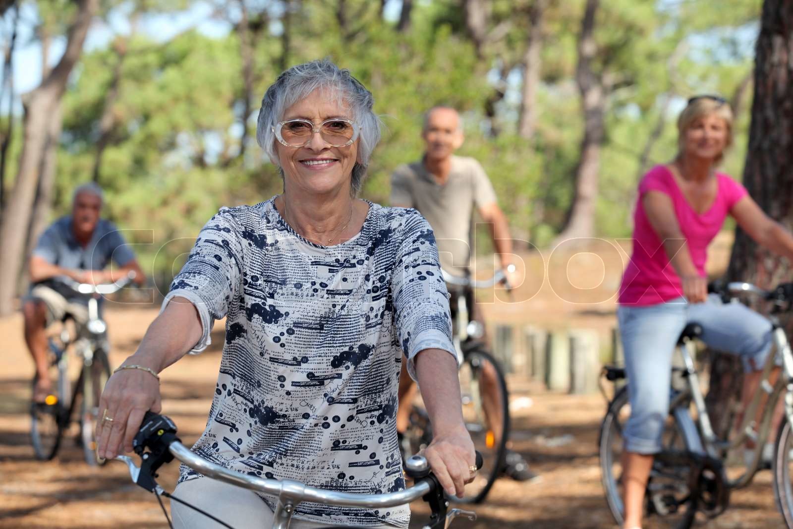 a 65 years old woman in first plan and three other people doing bike in ...