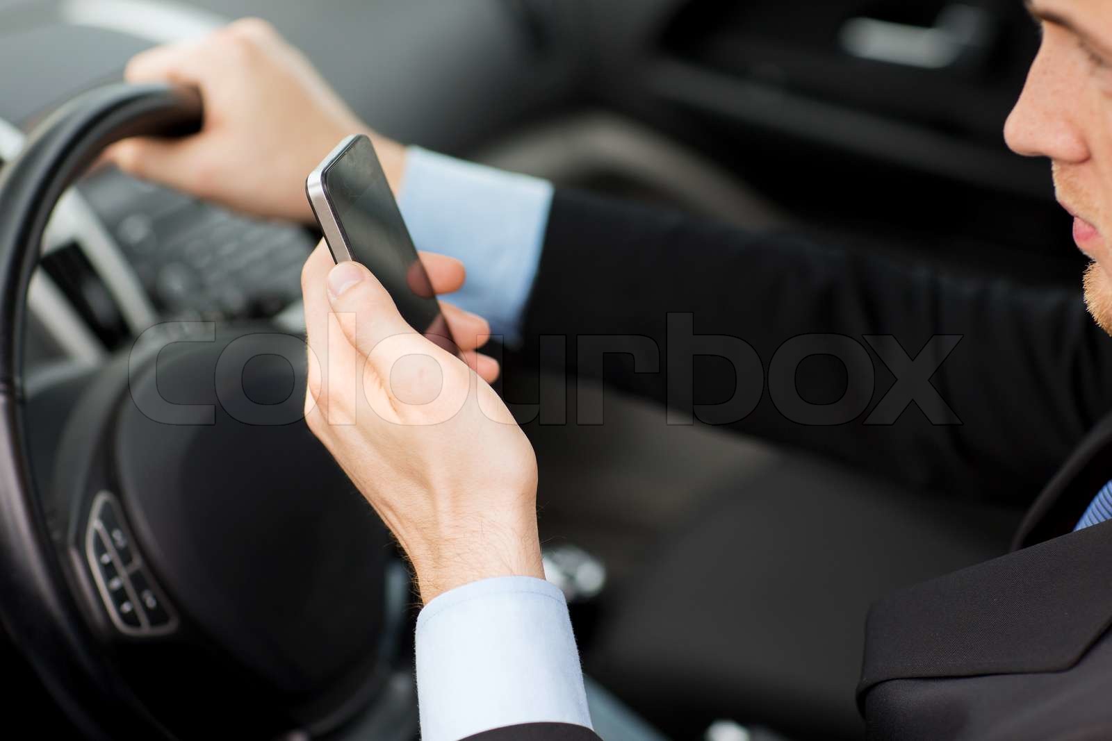 Mann mit Handy während der Fahrt das Auto | Stock Bild | Colourbox