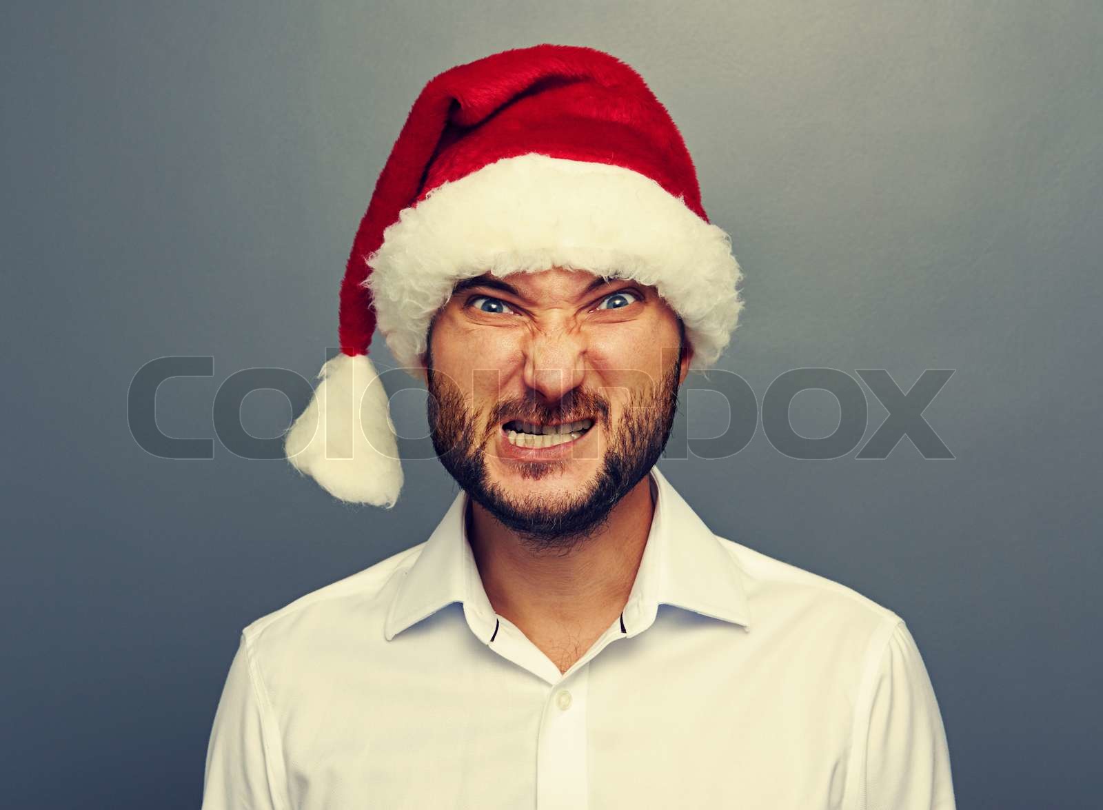 angry man in santa hat over grey | Stock image | Colourbox