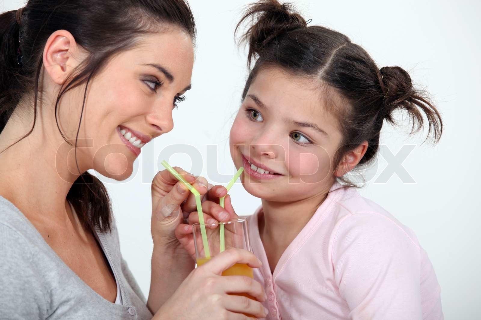 Woman sharing a glass of juice with her little sister | Stock image ...